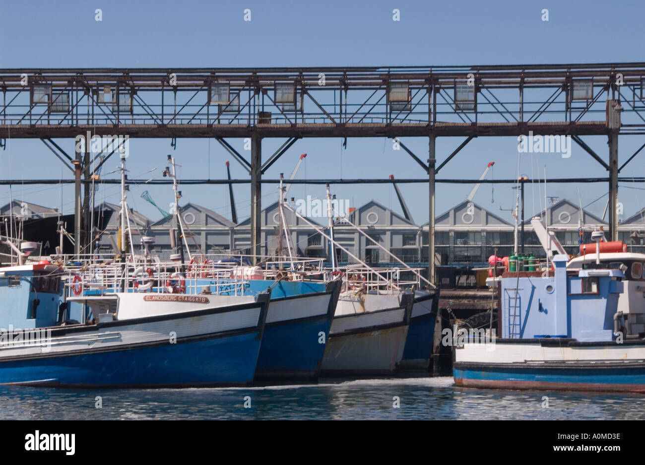 A row of hulls of ship with scaffolding and pointy roofed buildings in ...