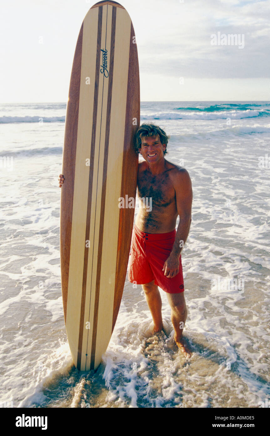 Surfer holding surfboard on Beach Stock Photo - Alamy