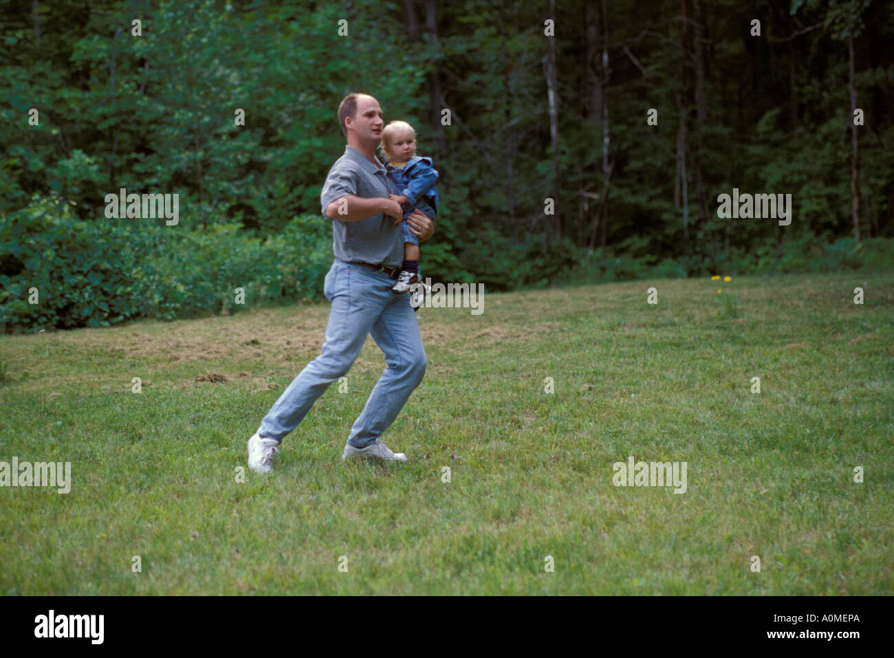 father carries son in arms 1 one young green grass happy frolic ...