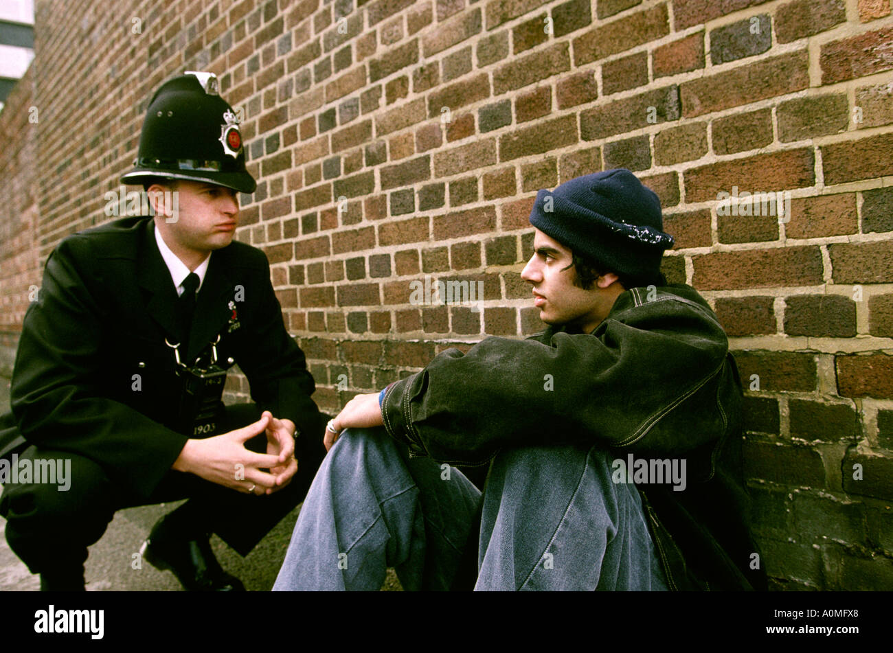 Policeman talking to young man posed by model policeman Stock Photo - Alamy