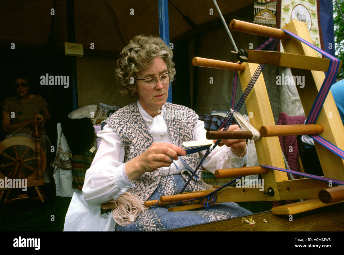 Crafts weaver working on a traditional Inkle loom weaving narrow fabric ...
