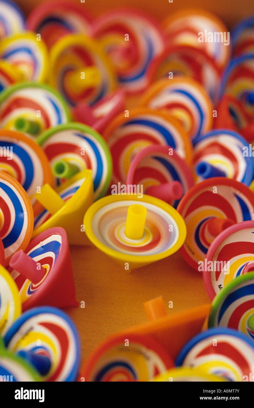 One yellow spinning top among other motionless multicolored spinning ...