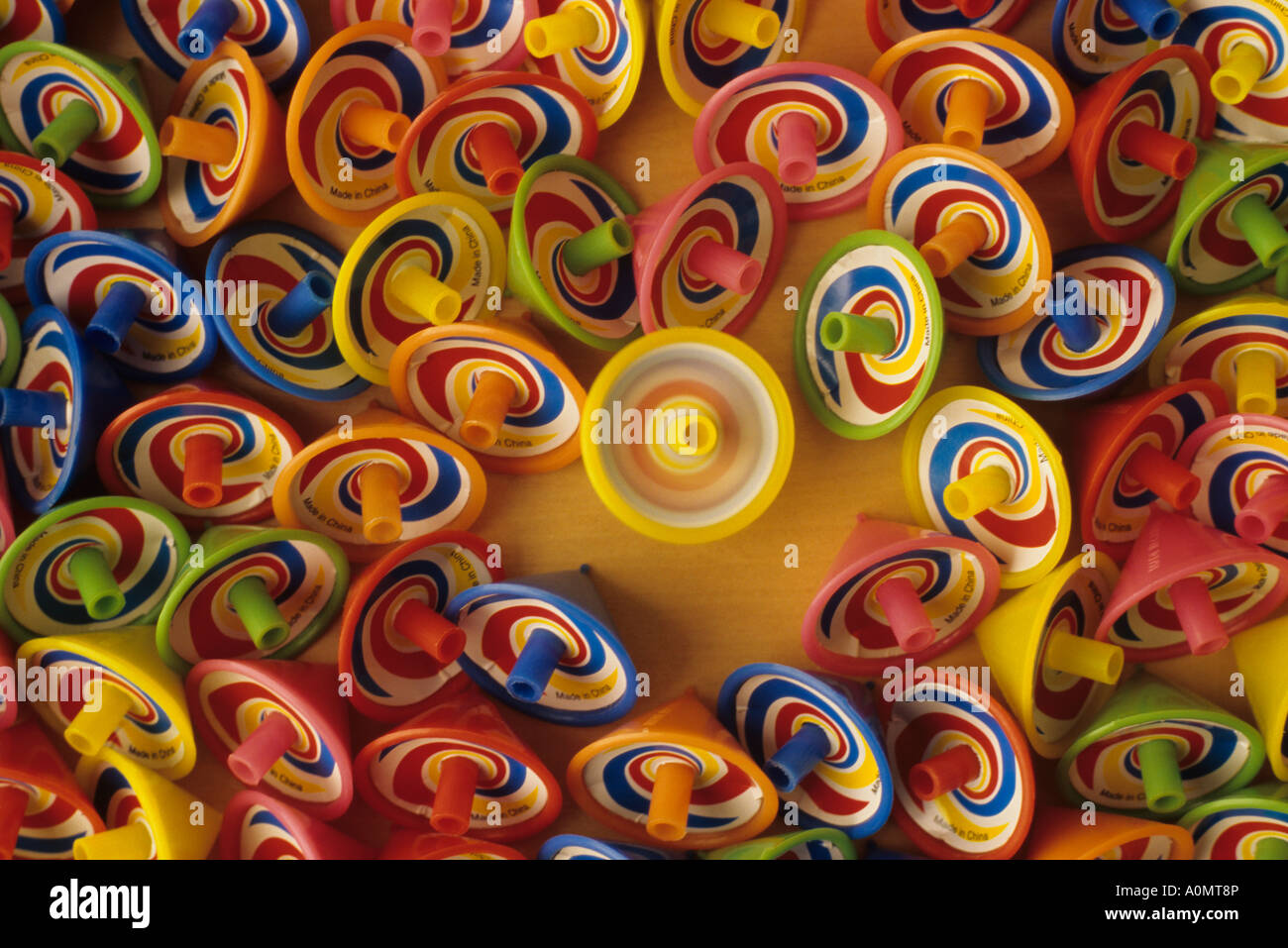 One yellow spinning top among other motionless multicolored spinning ...