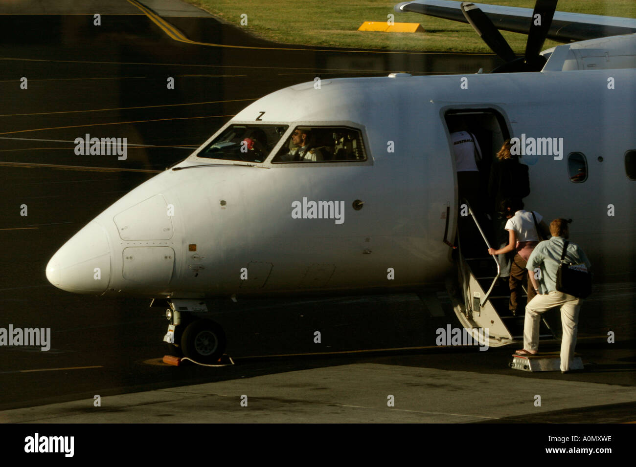 Passengers board a Dash 8 turbo prop airplane from the tarmac at ...