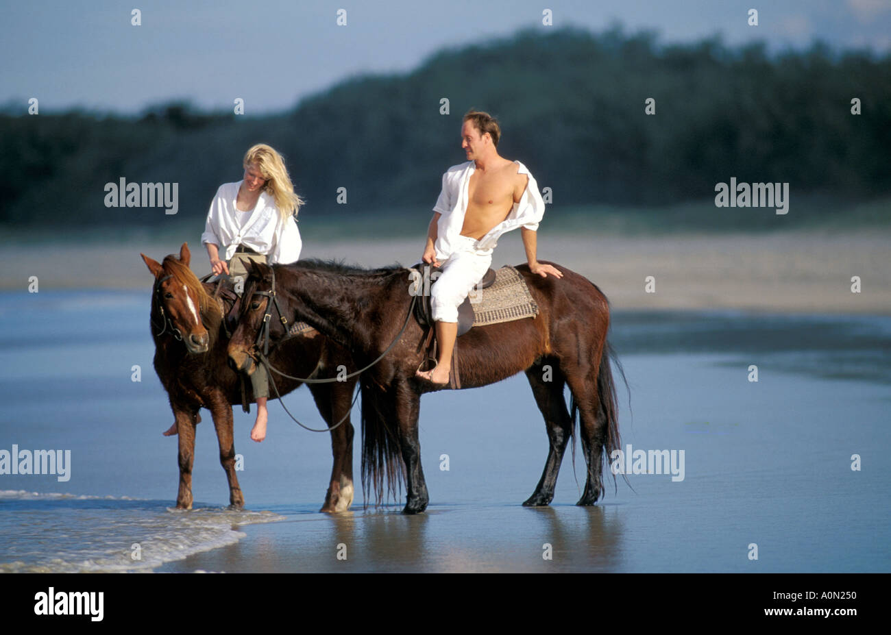 Australia Qld couple astride horses on beach Stock Photo - Alamy