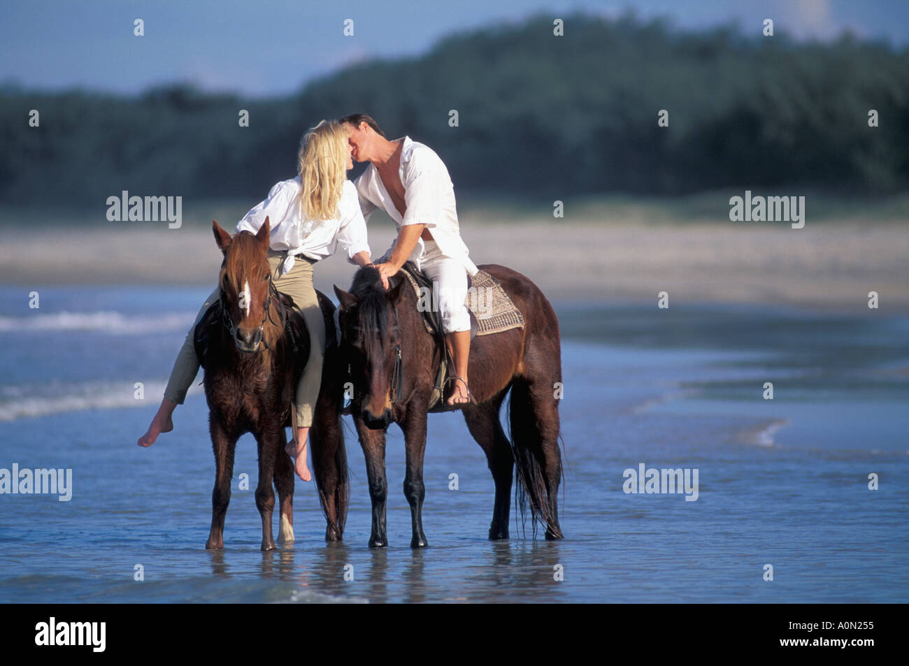 Australia Qld couple astride horses on beach Stock Photo - Alamy
