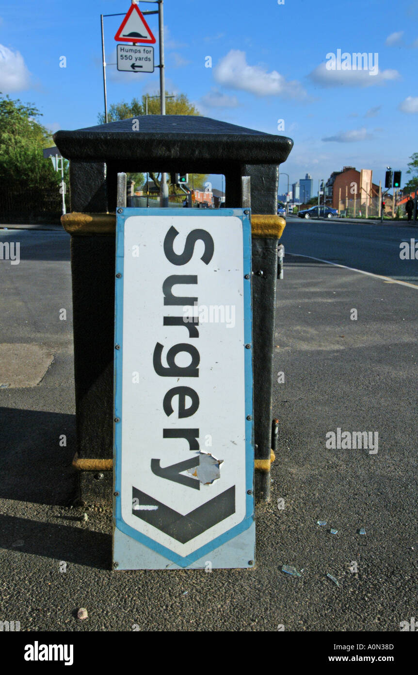 A Doctors surgery sign pointing to the ground leaning against a waste ...