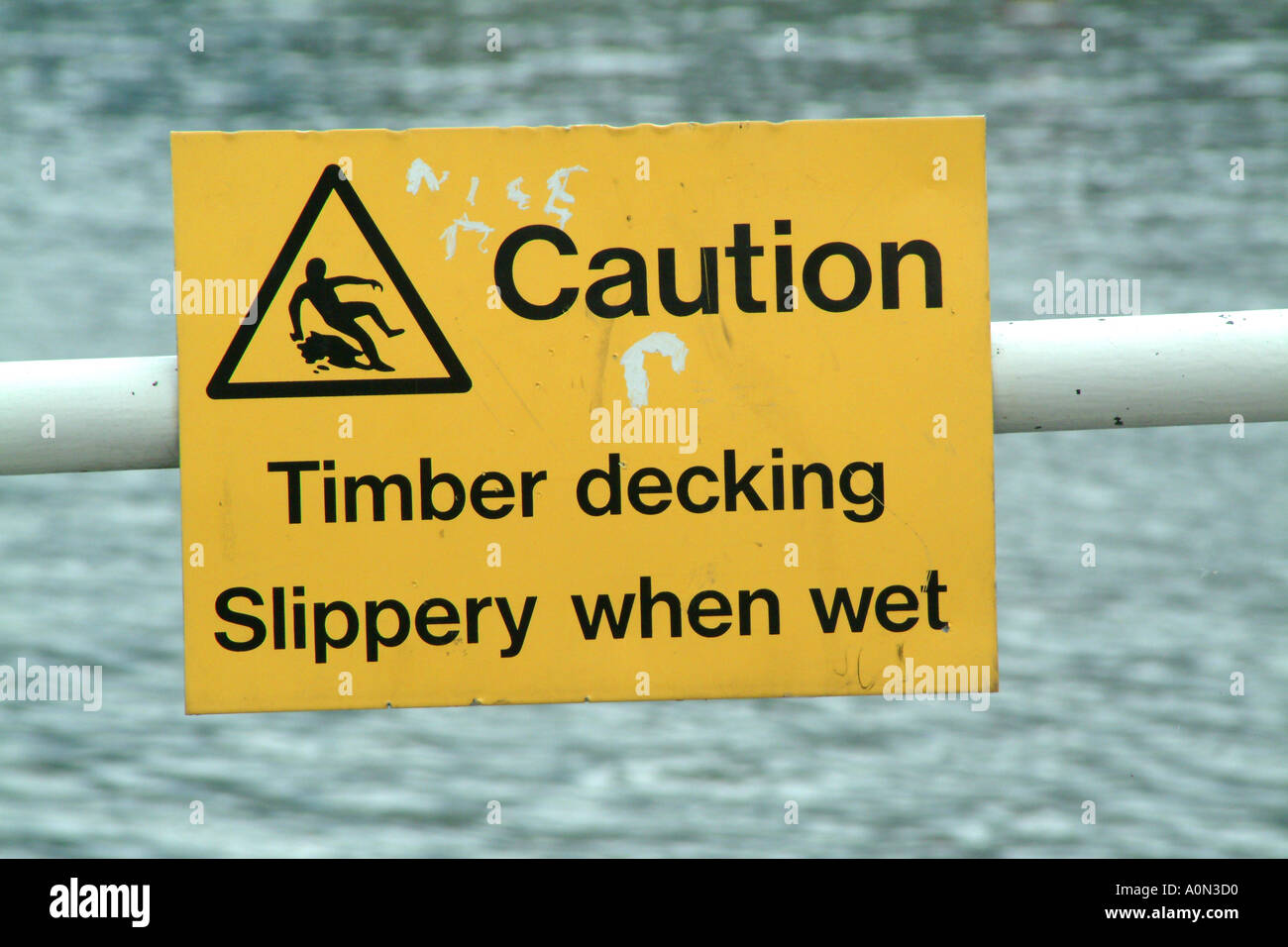 A caution sign warning that the timber decking is slippery when wet ...