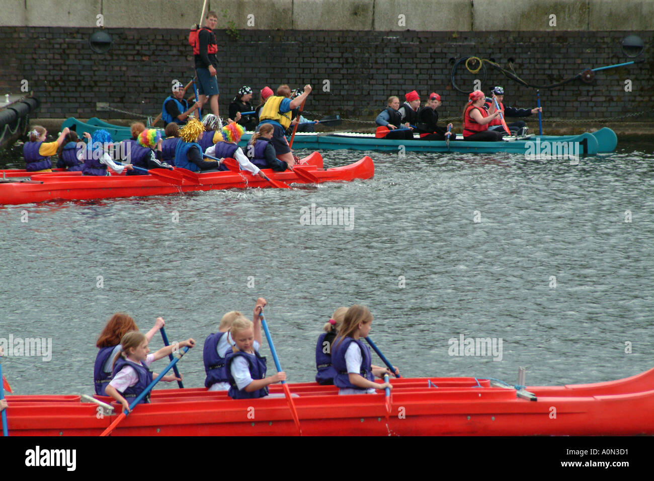Teams of children in multi man canoes line up for the start of a race ...