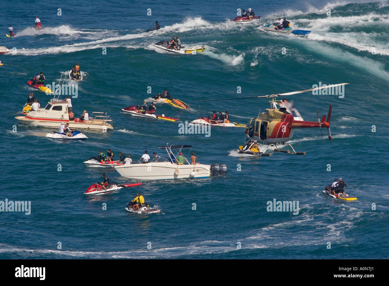 A helicopter filming a tow in surfer at Peahi, (Jaws) off Maui, Hawaii ...