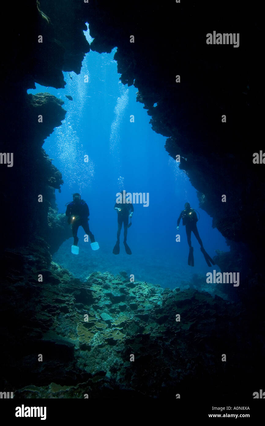 Three divers (MR) with lights pictured at a cavern enterance, Hawaii ...