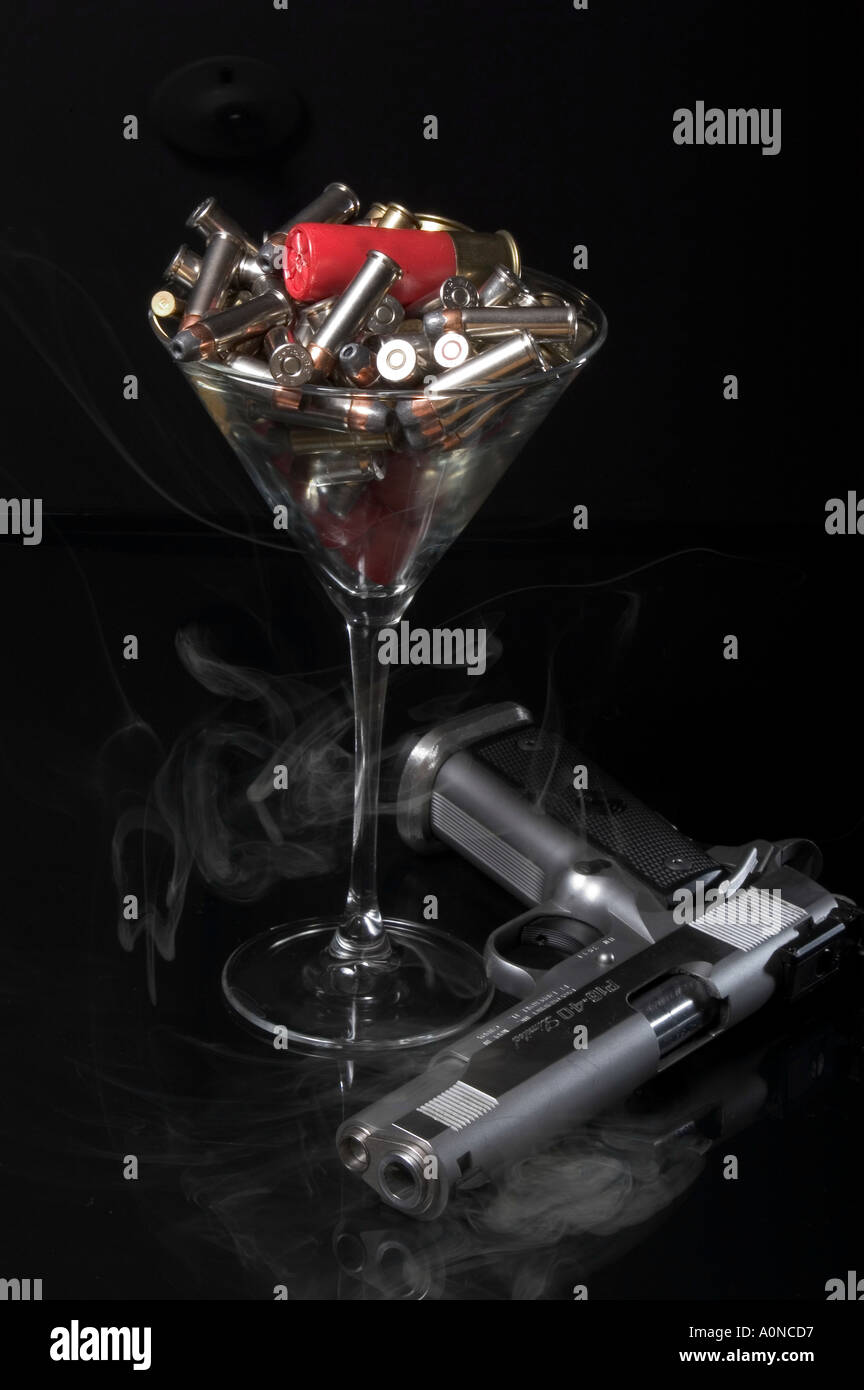 Martini glass filled with bullets and semi automatic pistol on black ...