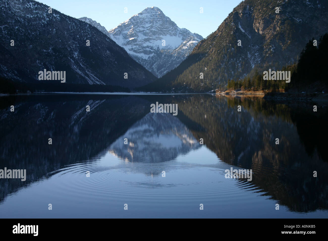 Ripples and reflections in an Alpine lake among mountains in Austria ...