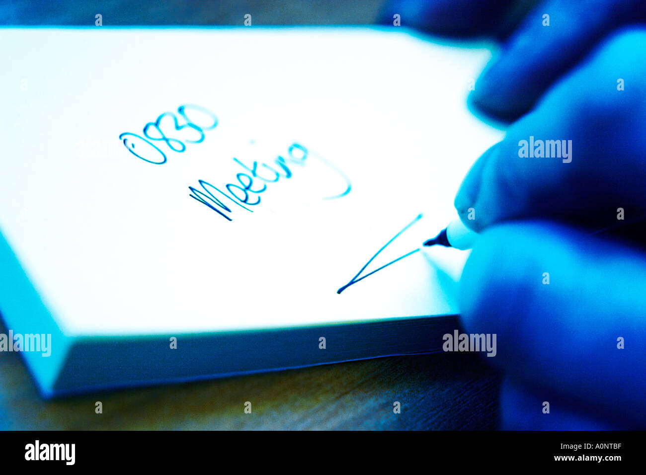 A hand writing a post it note reminder for a meeting at 8.30am Stock ...