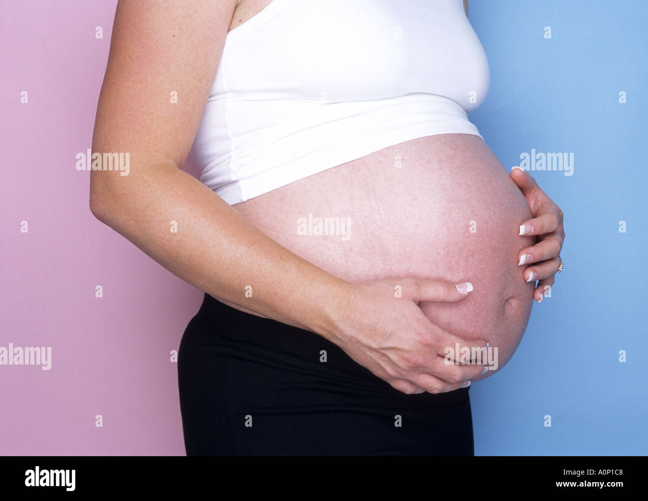 Lady with pregnant belly standing in front of half blue and half pink ...