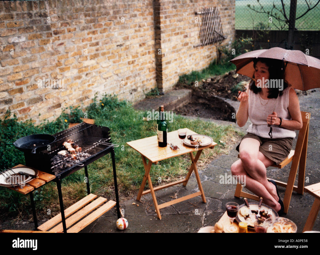 Barbeque in a small garden in England under an umbrella because of rain ...