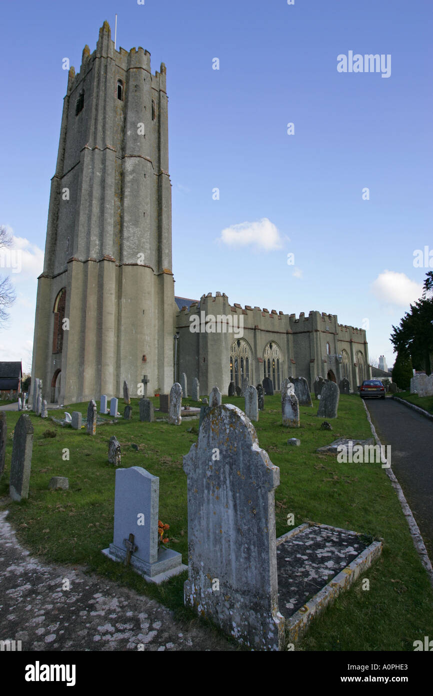 A traditional English church tower looms over a lush green graveyard ...