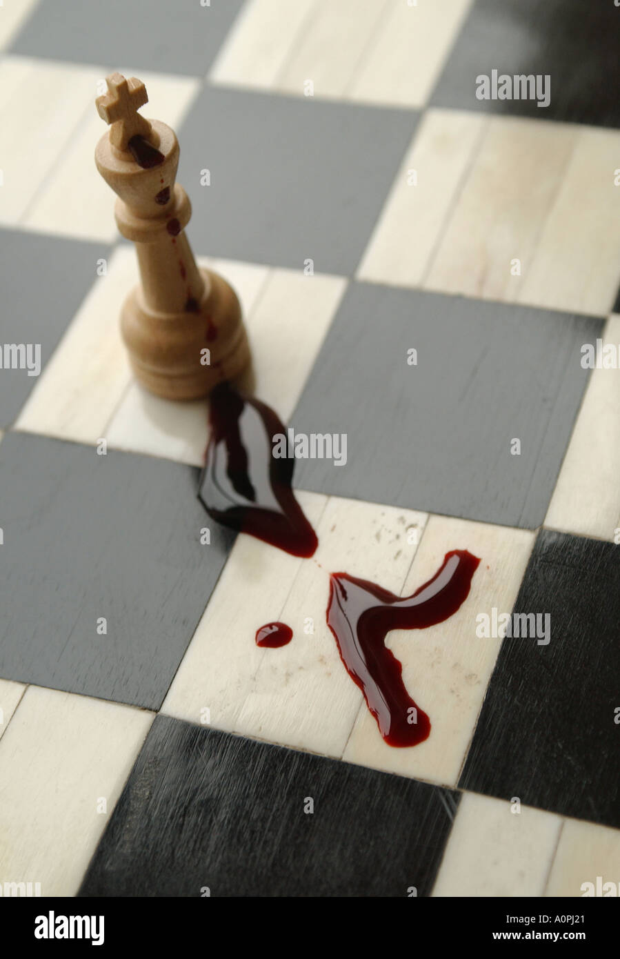 a king chess piece on a chess board with blood on it Stock Photo - Alamy