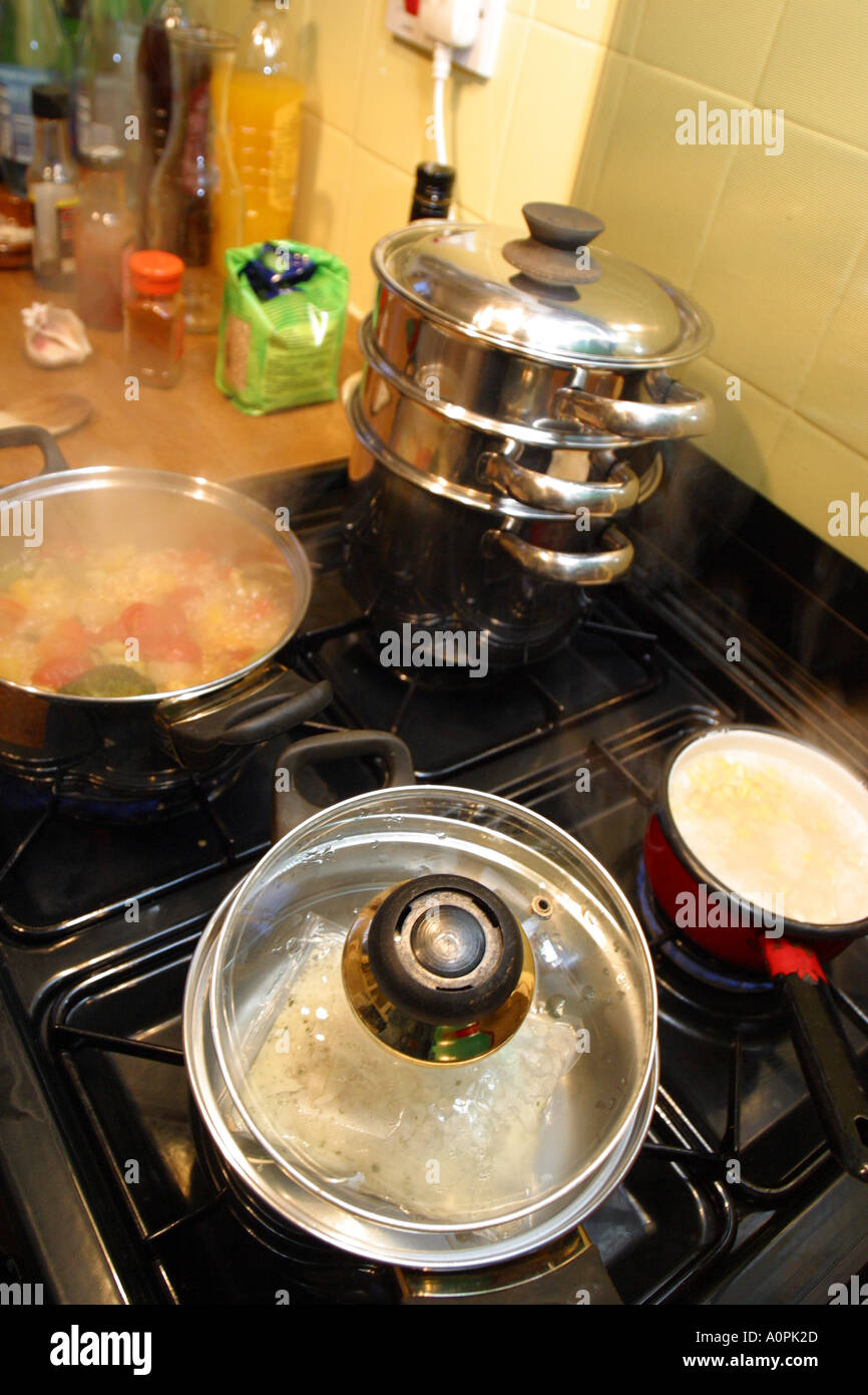 Fish and vegetables being cooked boiled and steamed on a gas cooker ...
