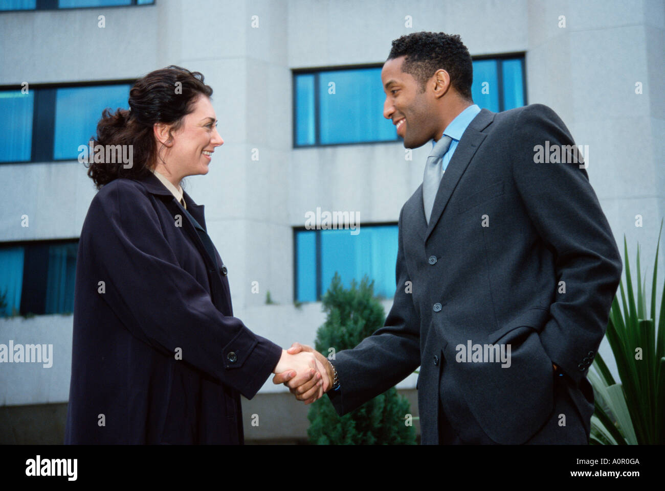 Young man and woman shaking hands outside city building Stock Photo - Alamy