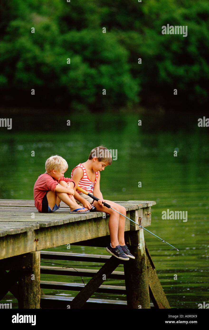Two boys river fishing off jetty Stock Photo - Alamy