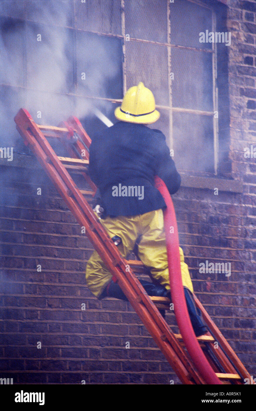 Fire fighter balancing on ladder while using water hose Stock Photo - Alamy