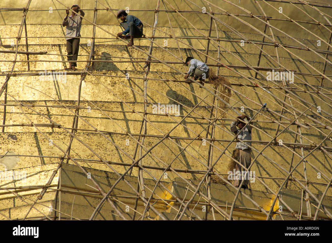 Workers on bamboo scaffolding applying fresh gold leaf to the Shwedagon ...