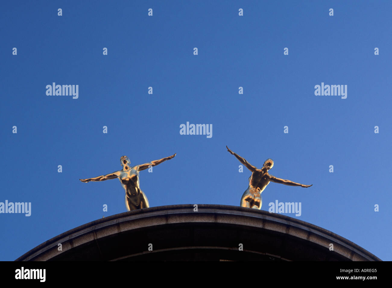 Pair of golden nude female diver statues on building edge overlooking ...