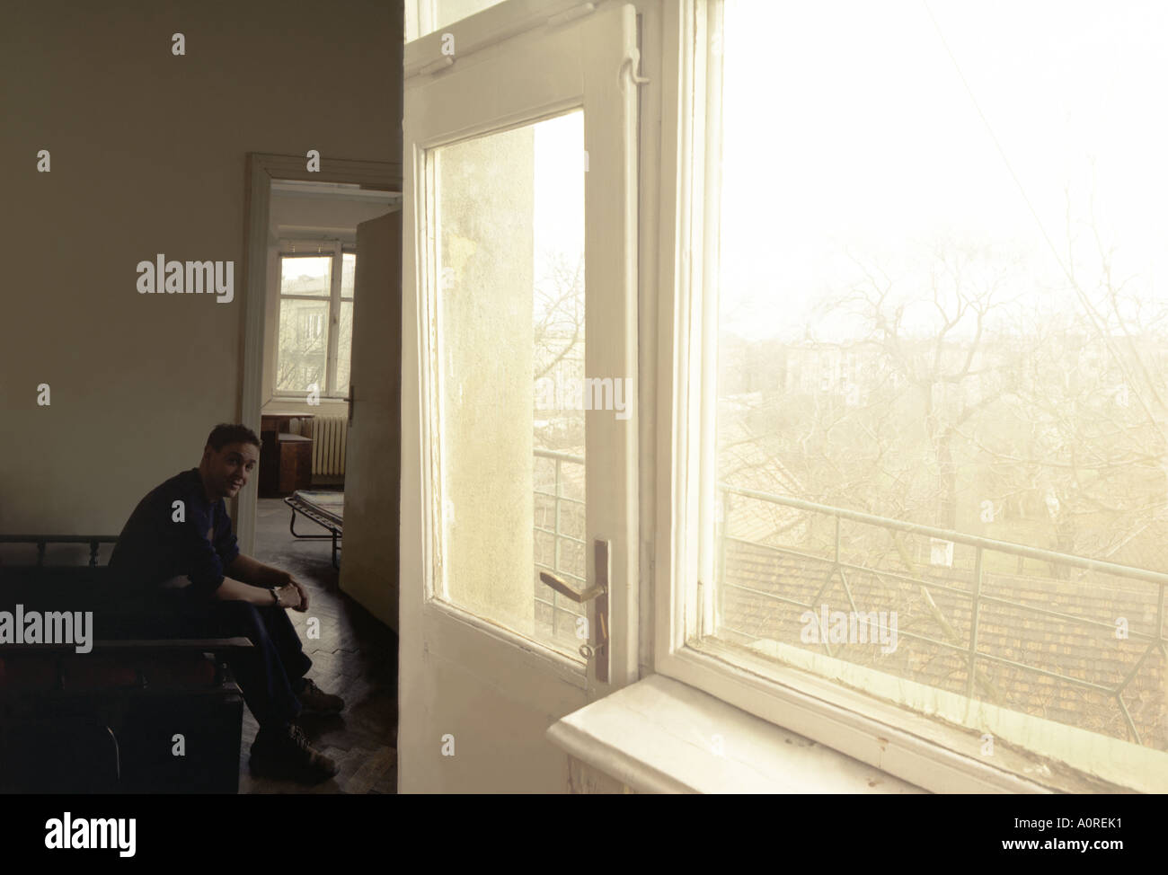 man sitting alone in empty flat flooded with daylight Stock Photo - Alamy