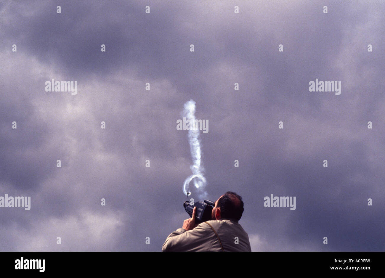 Man using video camera to film an aircraft in flight during a public ...