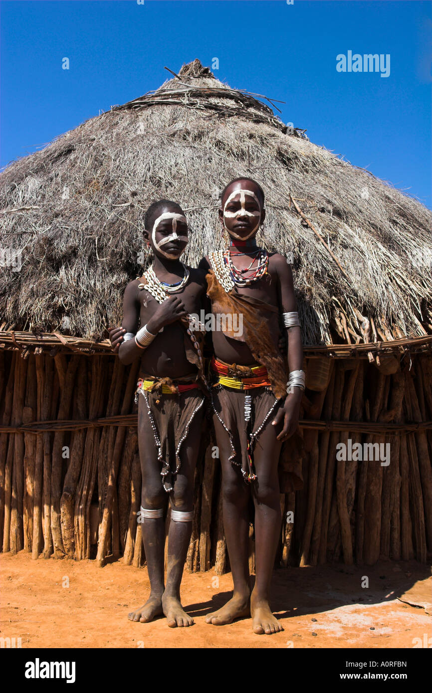 Hamer girls standing in front of house wearing traditional goat skin ...