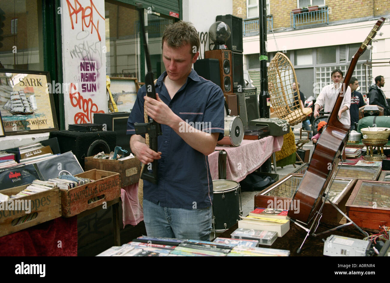 London, UK.. Brick Lane market stall, man examining gun Stock Photo - Alamy