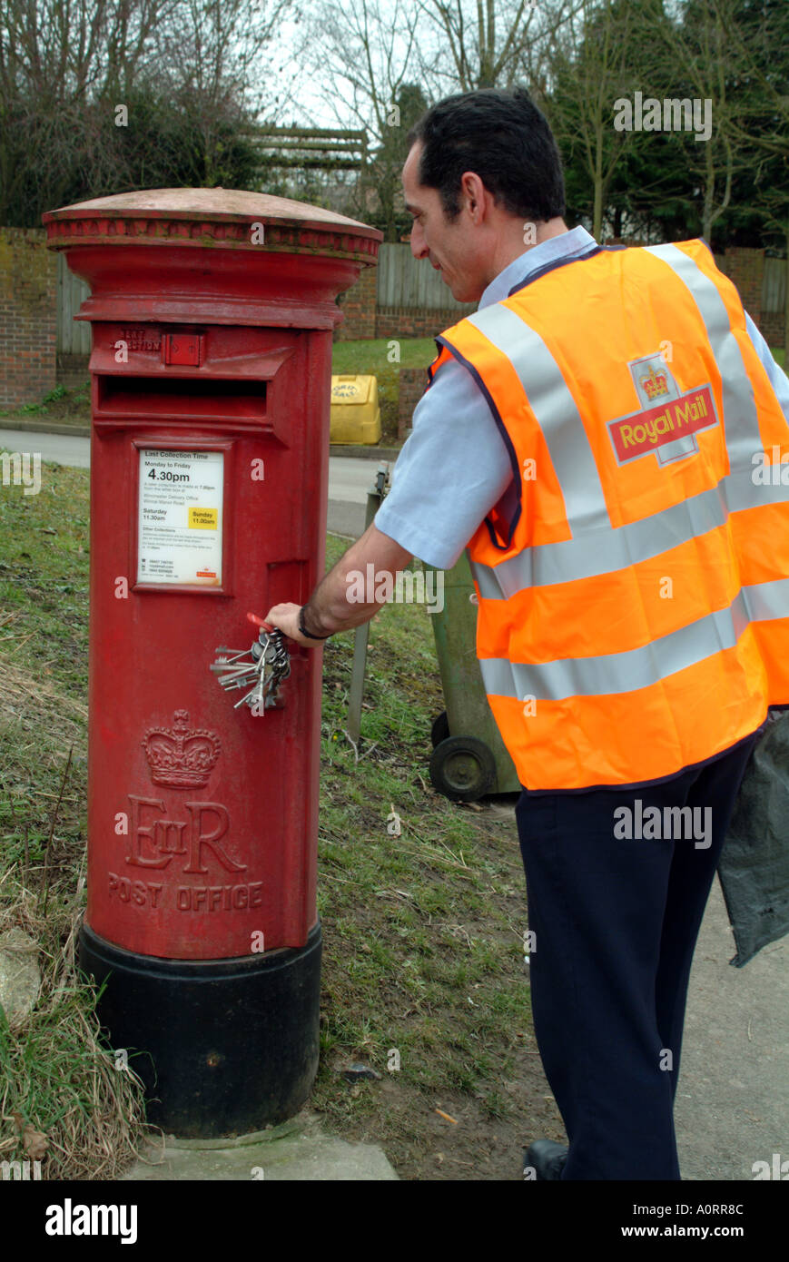 postman empties emptying letterbox box in rural location England UK ...