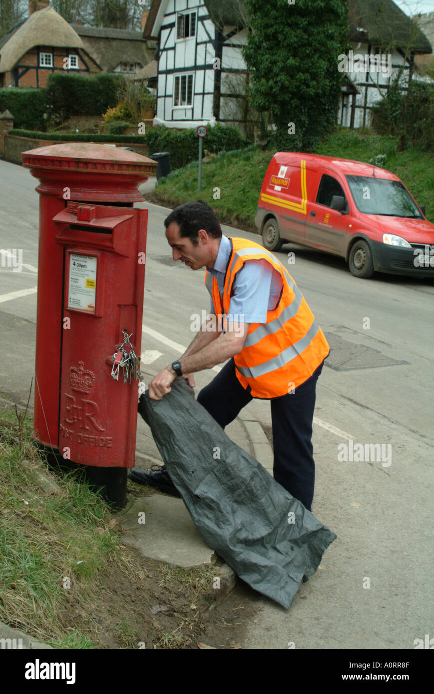 postman empties emptying letterbox box in rural location England UK ...