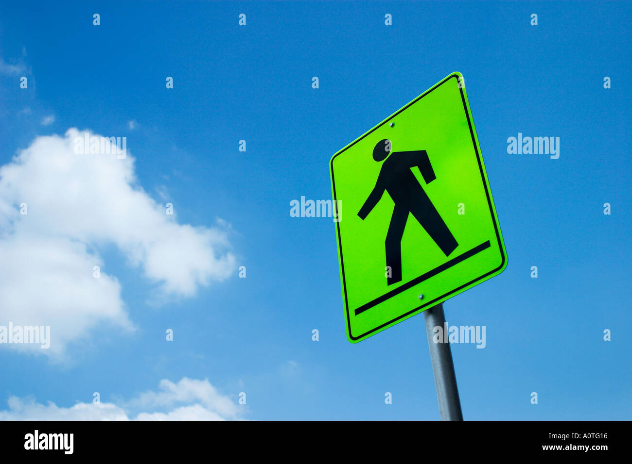 Green pedestrian crossing or walkway road sign with a blue sky ...