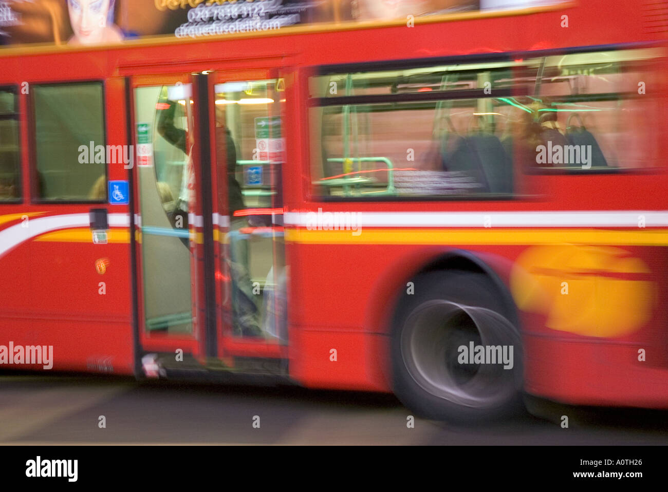 Red double decker bus whizzing through Piccadilly Circus in London ...