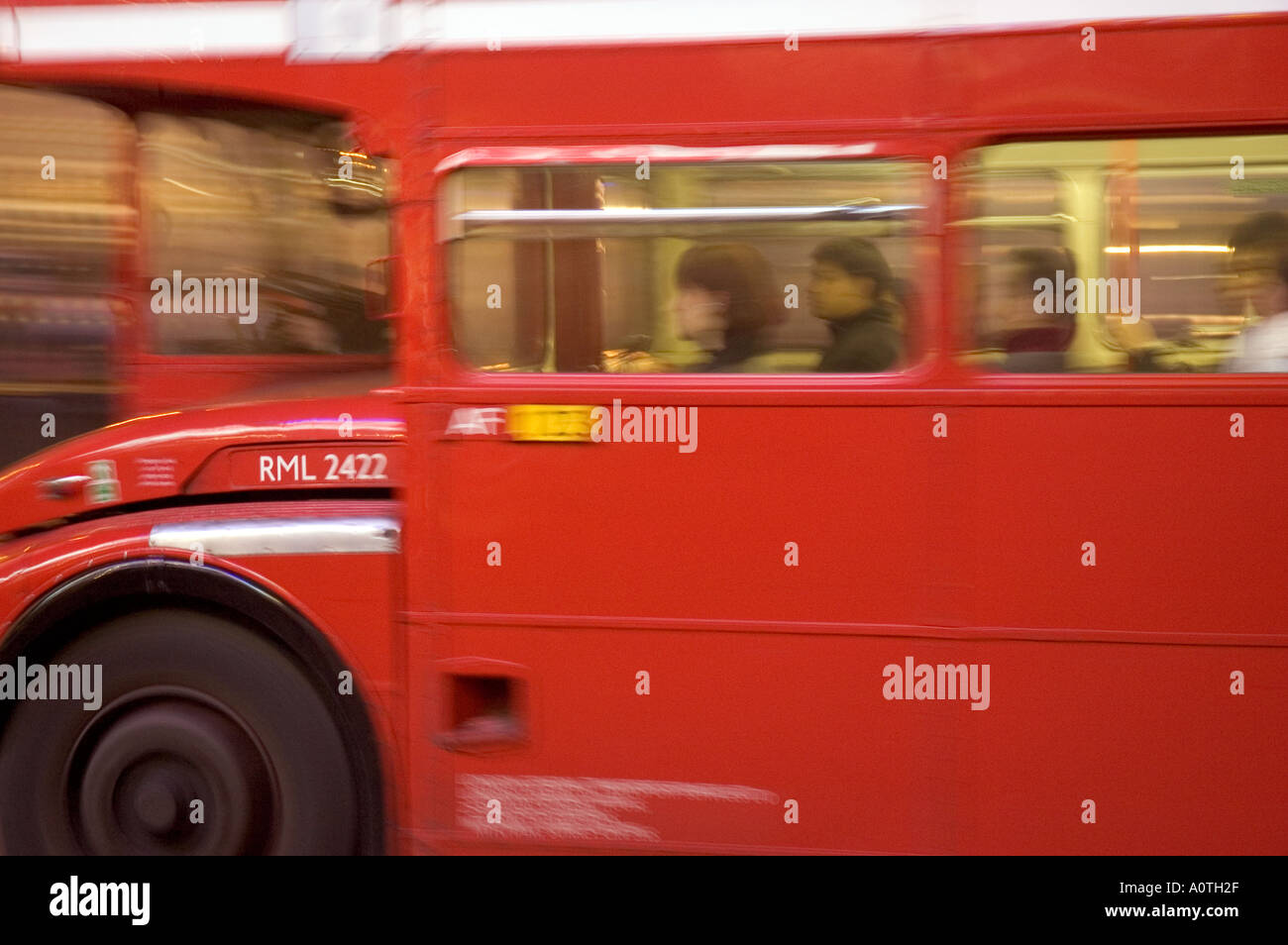 Red double decker bus whizzing through Piccadilly Circus in London ...