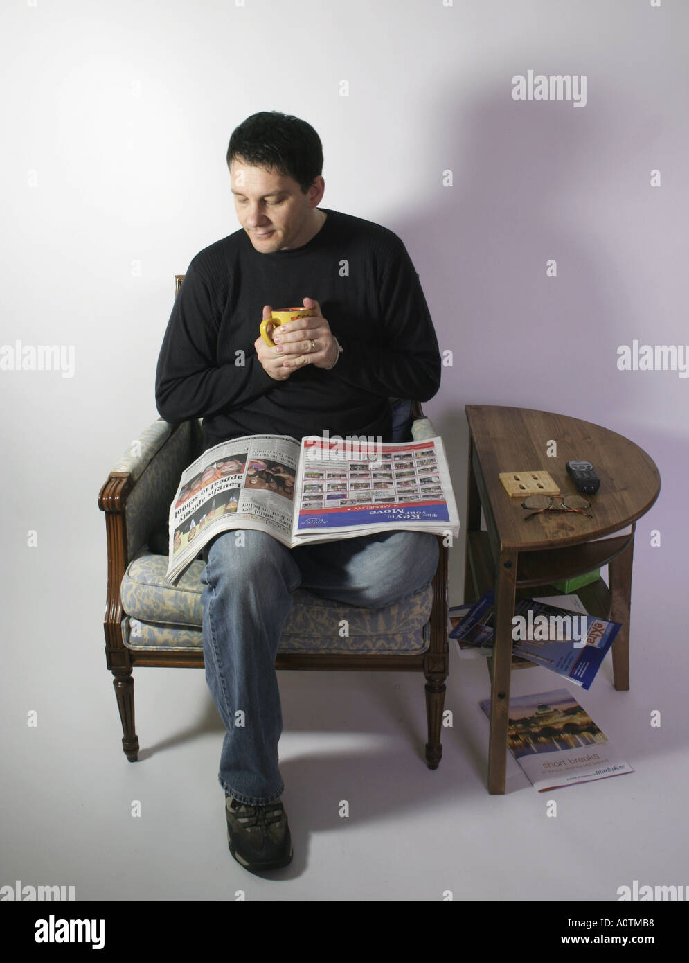 Man sat down looking at the newspaper Stock Photo - Alamy