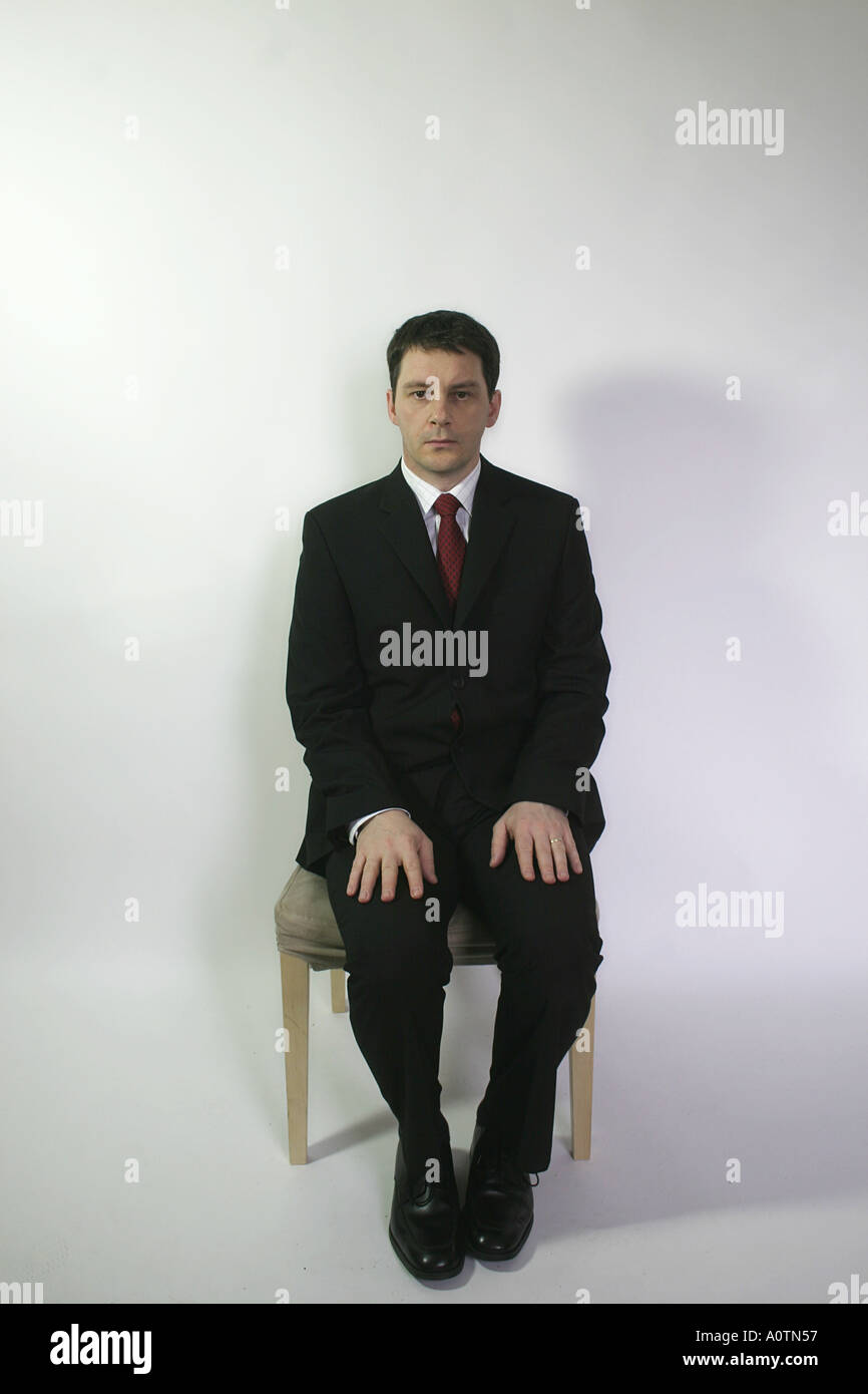 Man in suit sitting formally looking straight ahead Stock Photo - Alamy