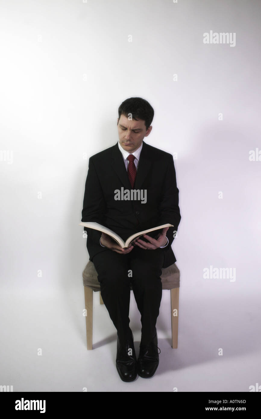Man in suit sits formally reading a book Stock Photo - Alamy
