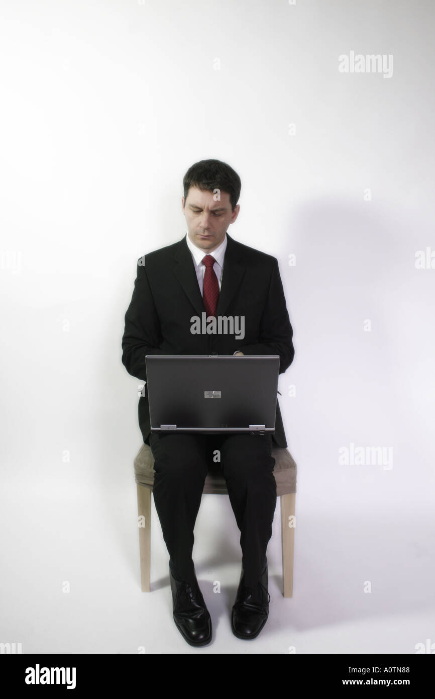 Man in suit sitting down with a laptop computer Stock Photo - Alamy
