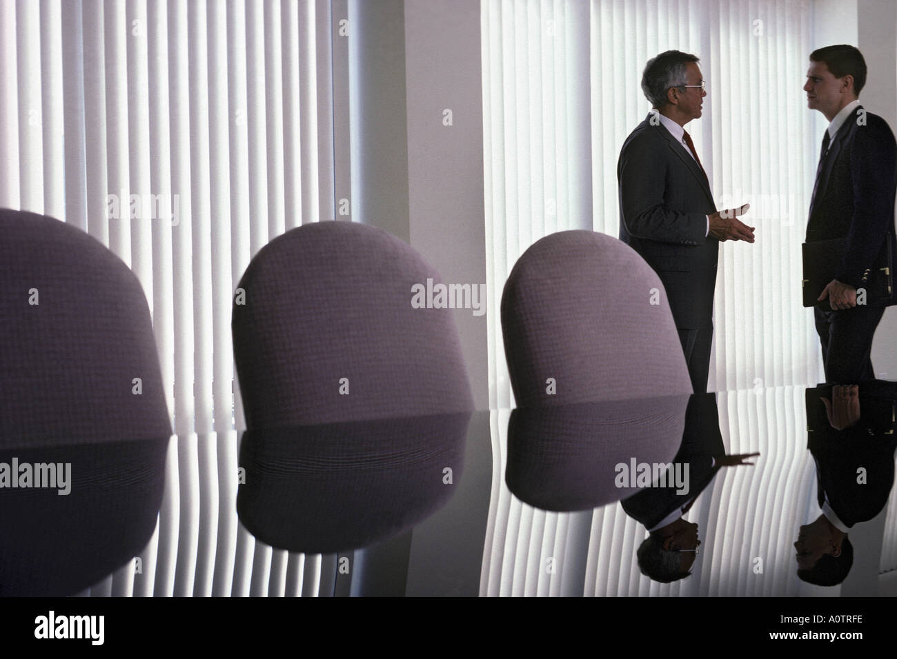 Two executives in discussion behind a glass top conference table with a ...