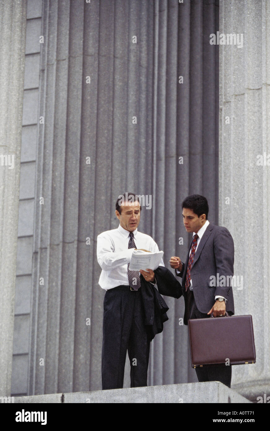 Two business executives are dwarfed by the massive columns outside the ...