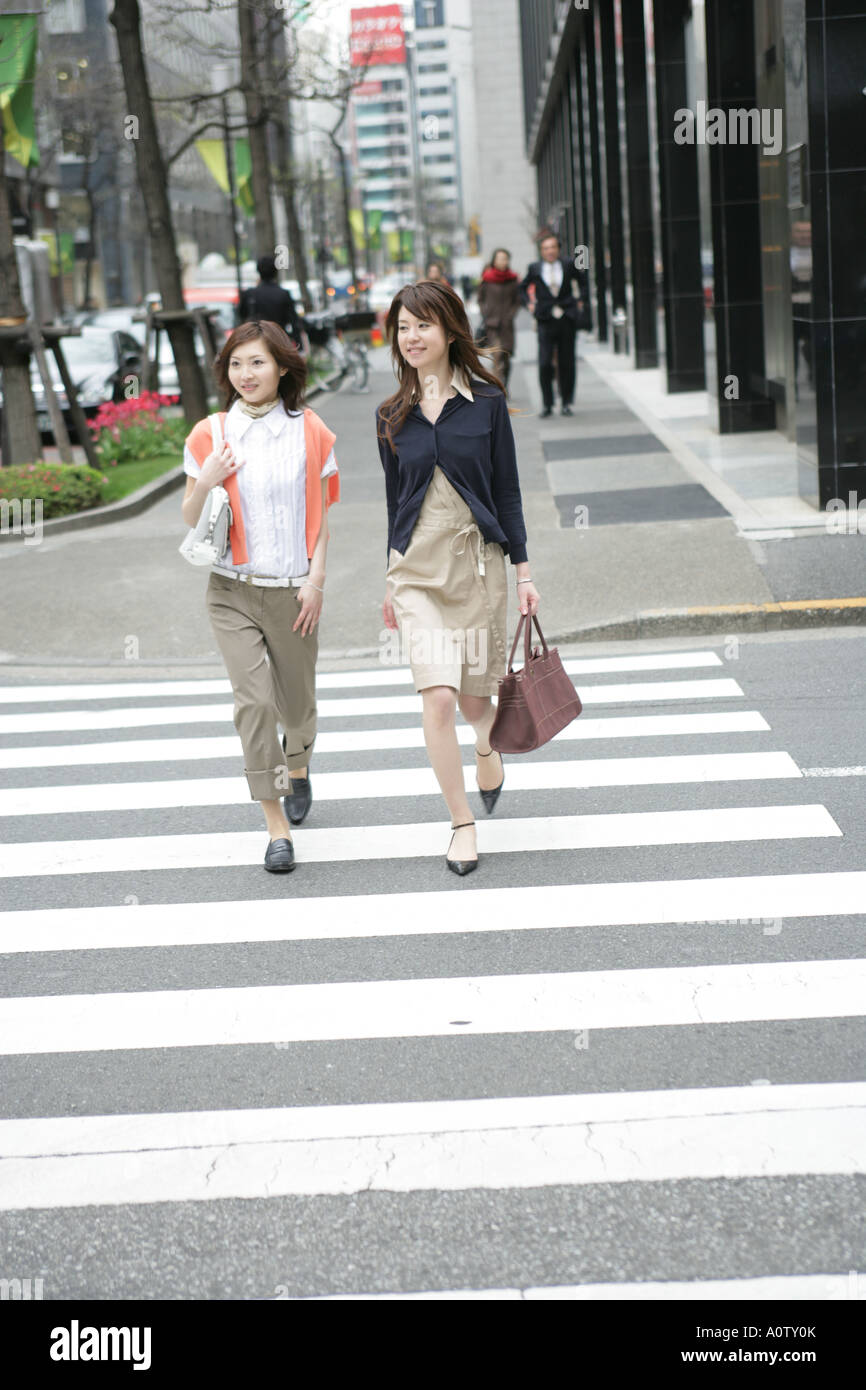 Two young women crossing a road on a zebra crossing Stock Photo - Alamy