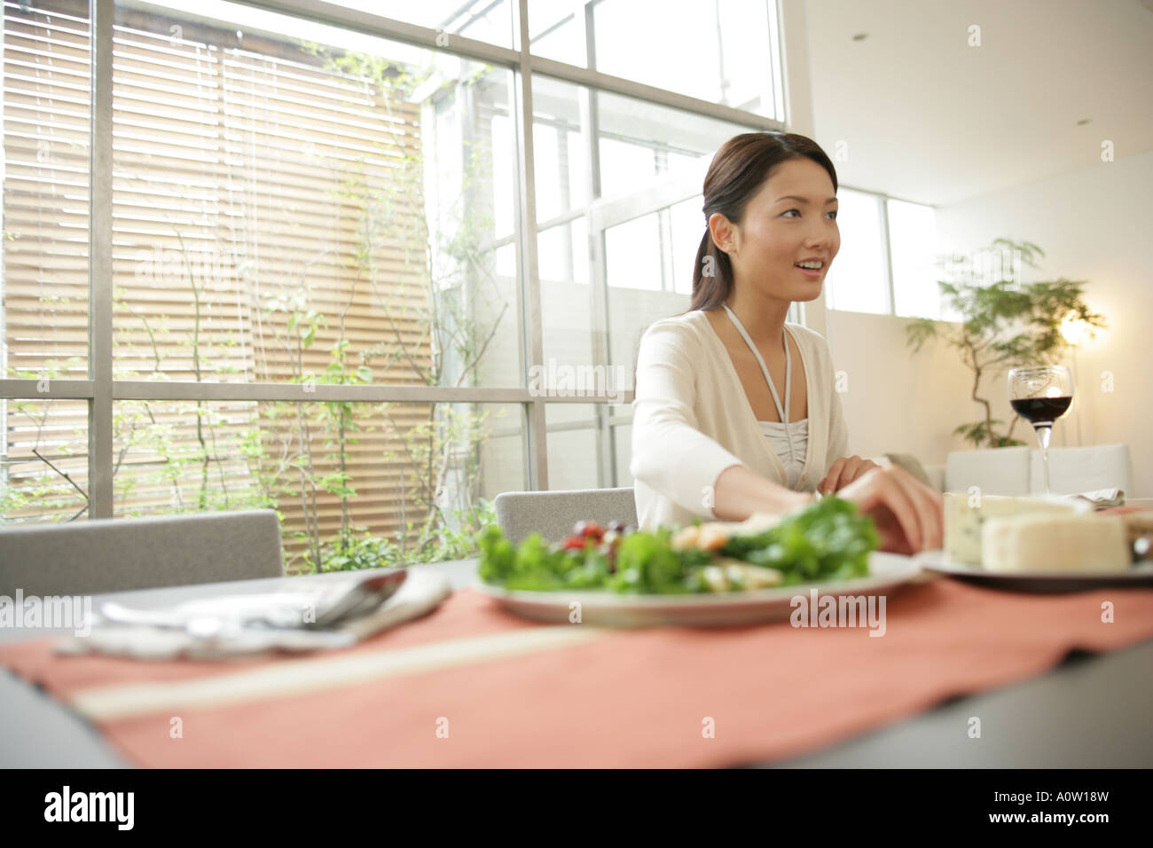Young woman sitting at the dining table Stock Photo - Alamy