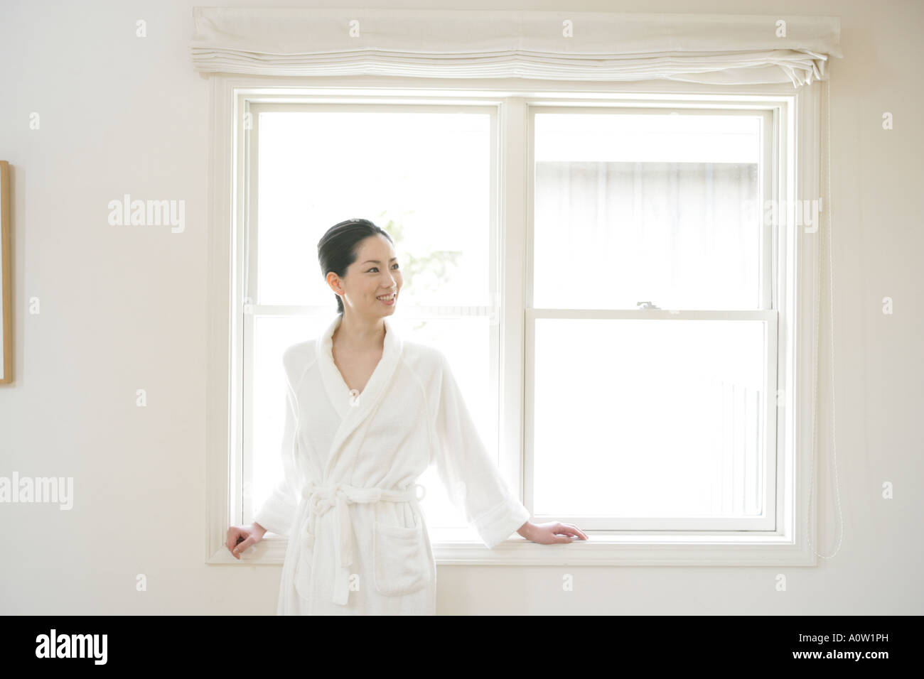Young woman leaning against a window Stock Photo - Alamy