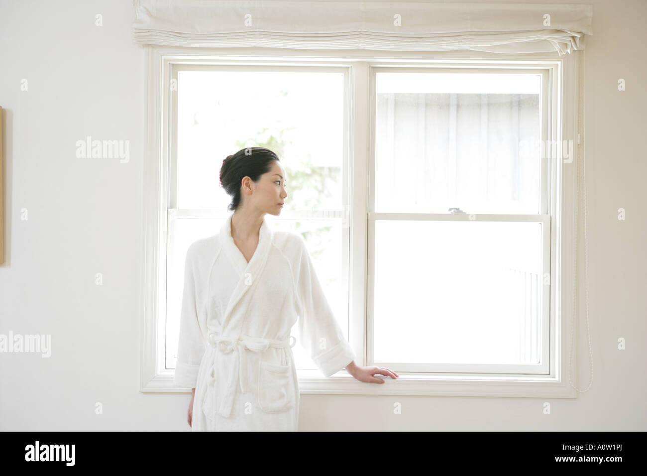 Young woman leaning against a window Stock Photo - Alamy