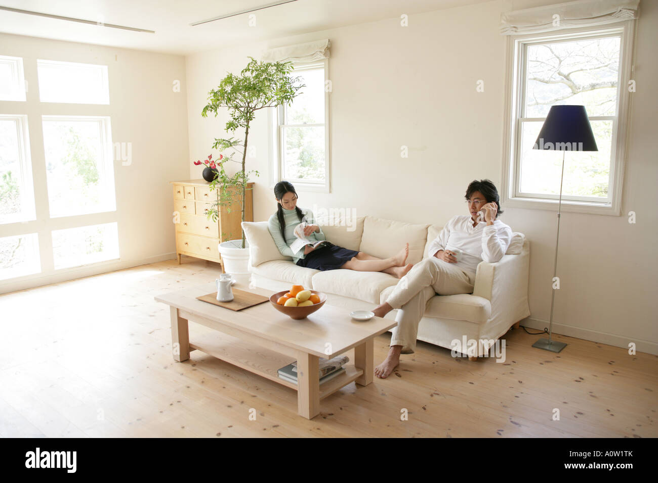 Young woman reading a magazine with a young man talking on a mobile ...