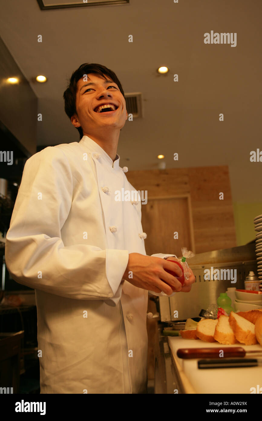 Side profile of a male chef standing at a kitchen counter and laughing ...