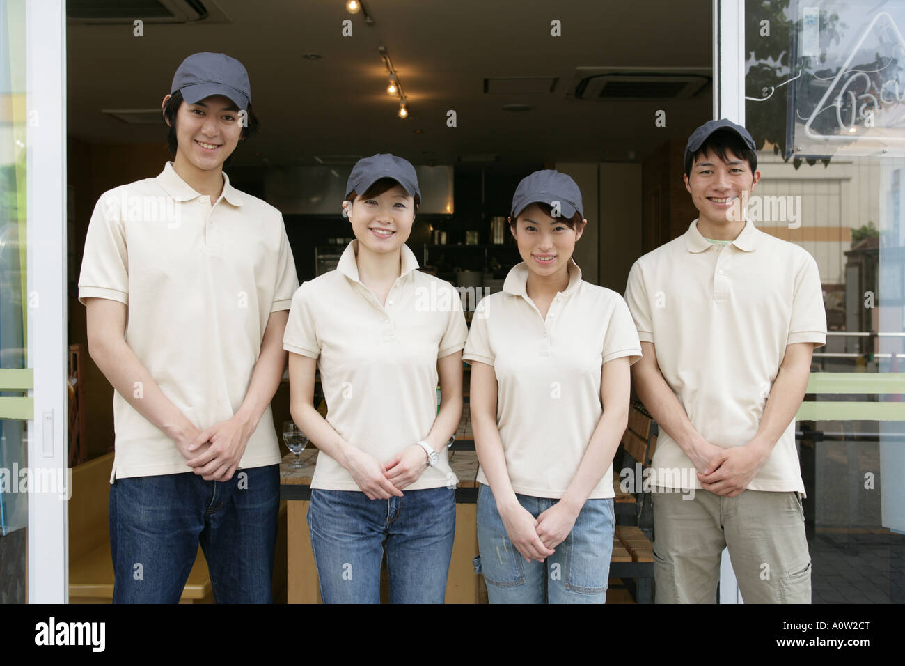 Portrait of two waiters with two waitresses standing in front of a ...